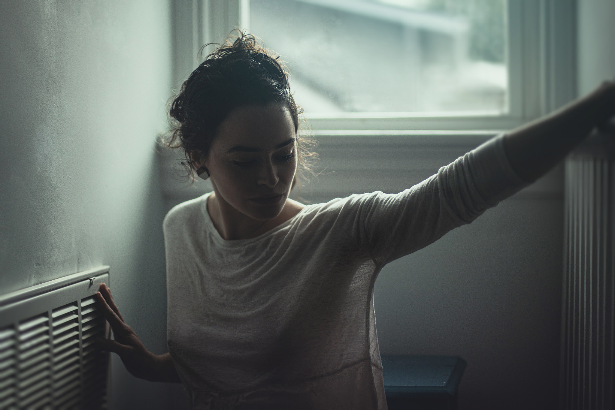 Young Woman Touching Radiator by Window Light | people photo by Jake ...