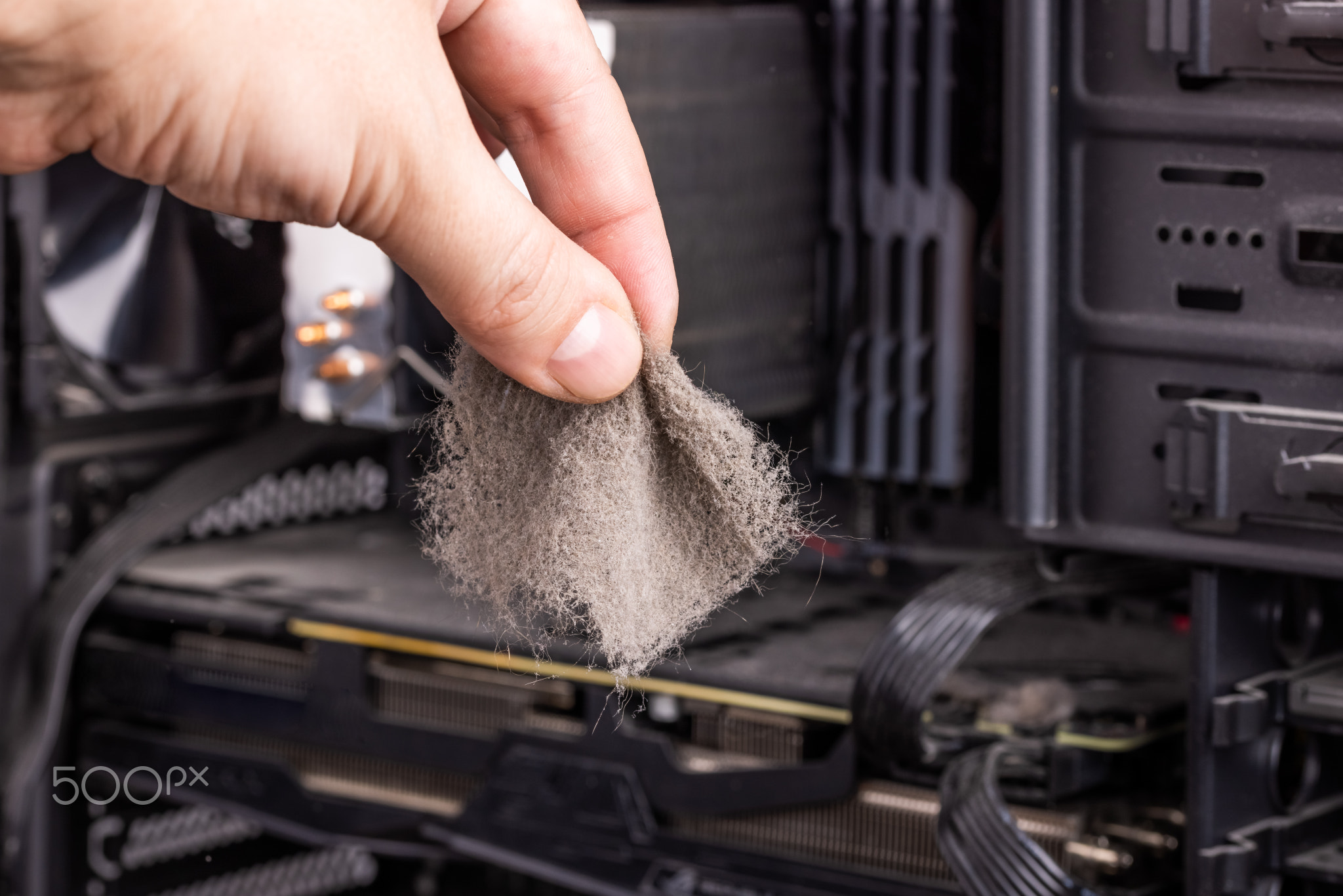 bare caucasian hand holding dust clog in front of opened pc case by teh ...