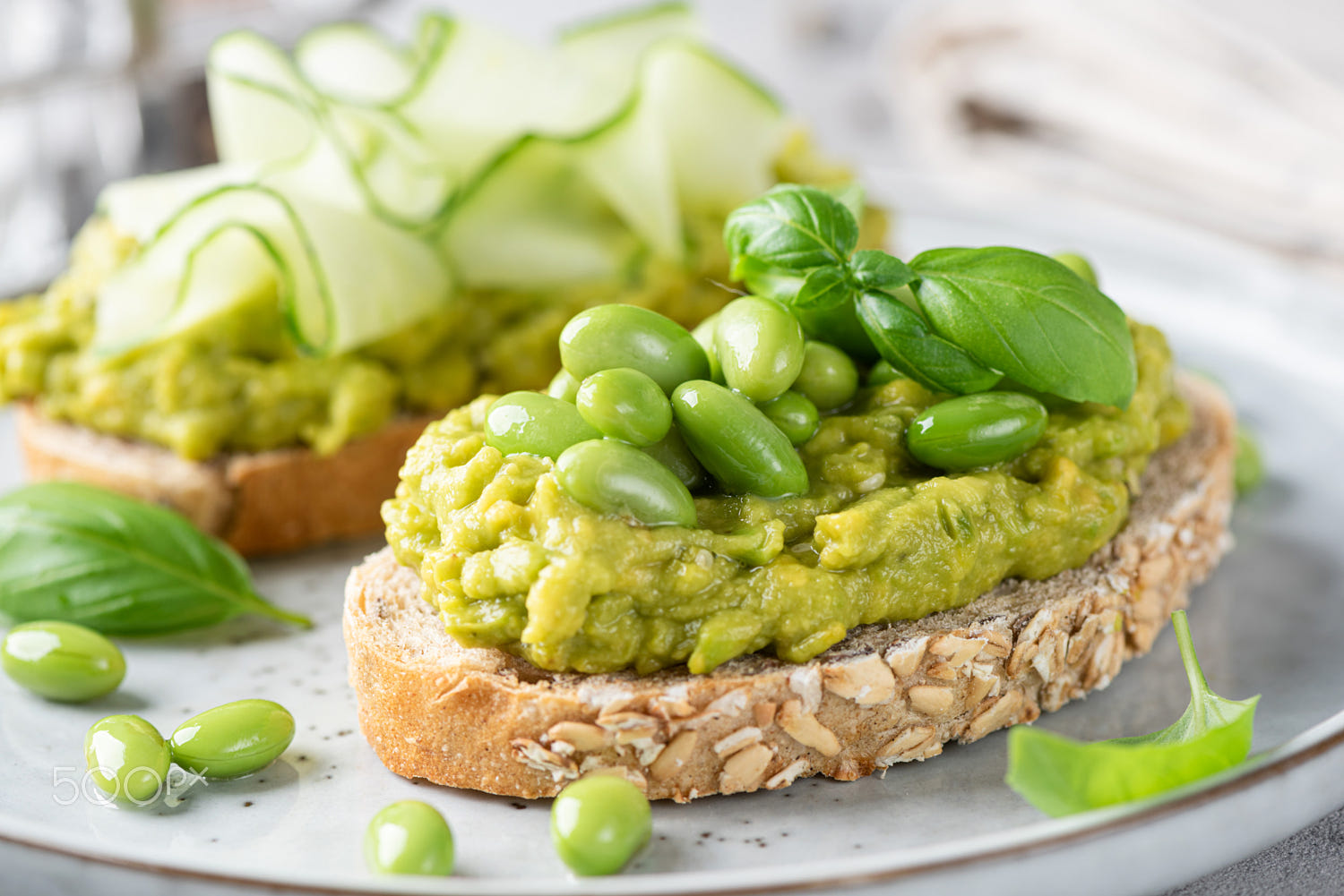 Fresh green avocado toasts with edamame beans and cucumber toppings by ...