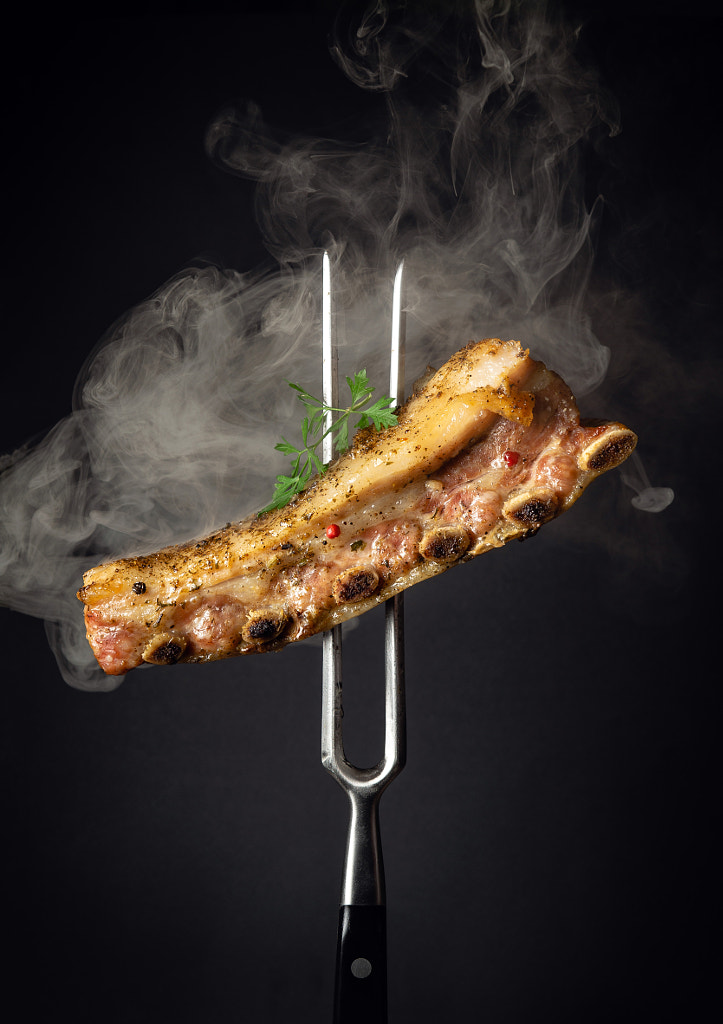 Oven-baked pork ribs on a fork with steam. The concept of fast and ...