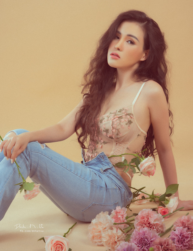 Portrait of young woman sitting by flowers against wall by Dinh Nhat Vu / 500px