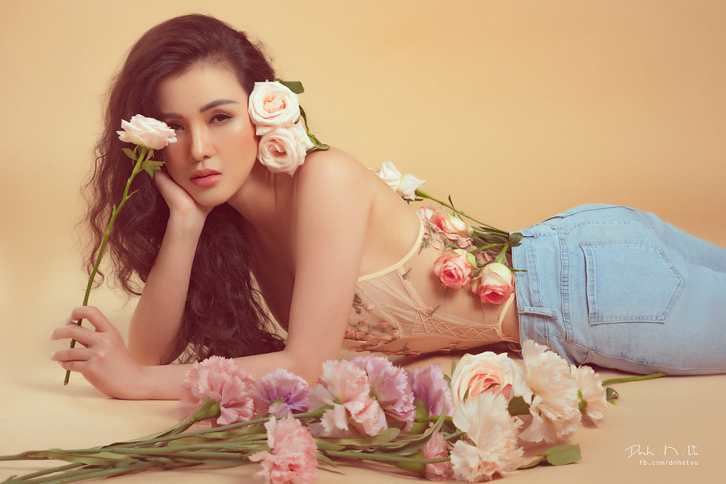 Portrait of beautiful young woman with flowers against wall by Dinh Nhat Vu / 500px