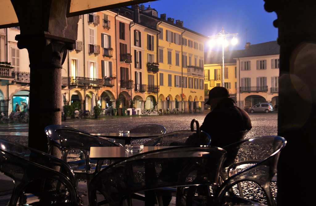 Man sitting on chair against buildings in city at night by Carlotta ...