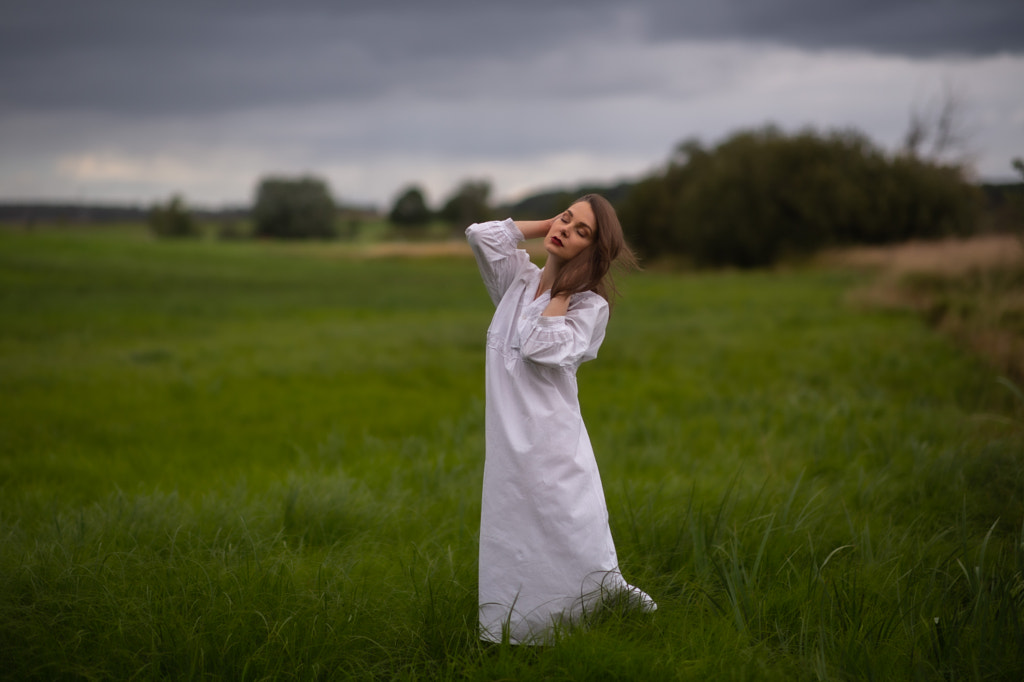 Young woman standing on field against sky by Frank Reinbold / 500px