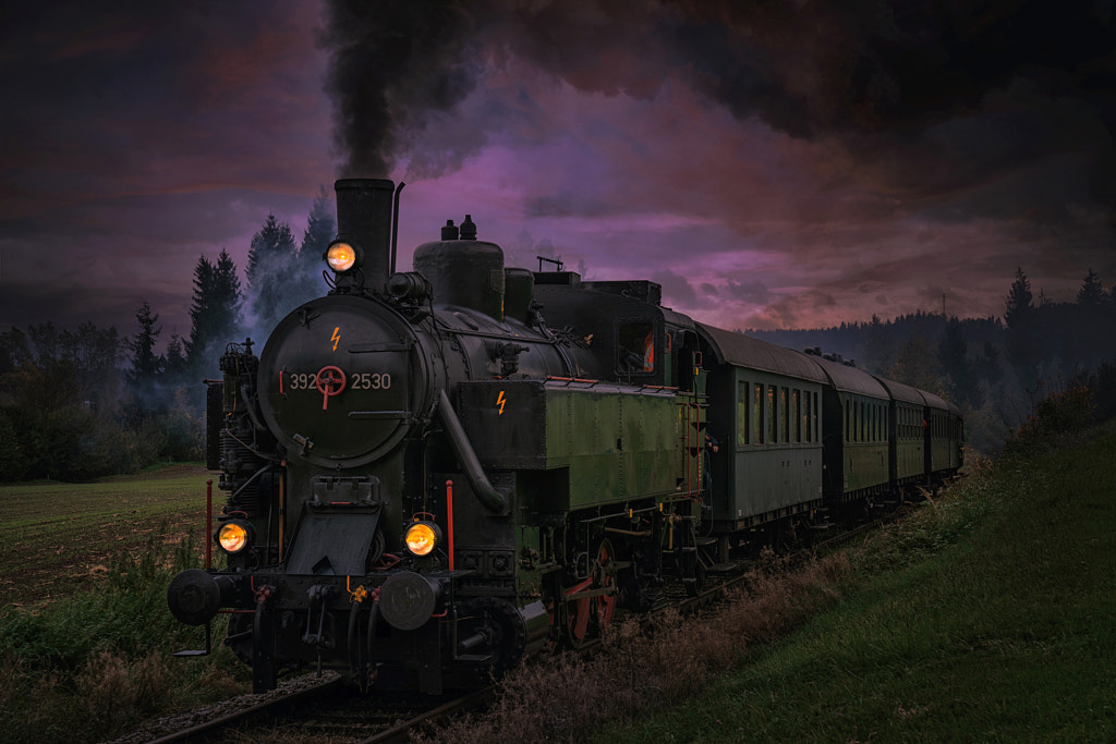 View of steam train on railroad track against sky by Hubert Bichler / 500px