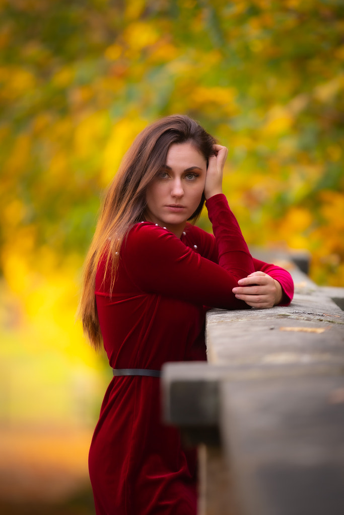 Portrait of young woman standing by railing during autumn by Frank ...
