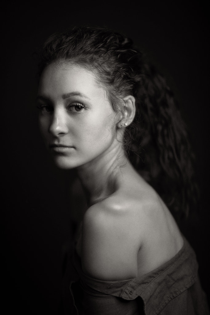 Portrait of young woman against black background by Zachar Rise / 500px