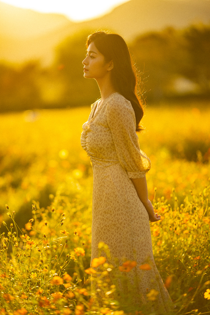 Beautiful young woman standing on field by JH KIM / 500px