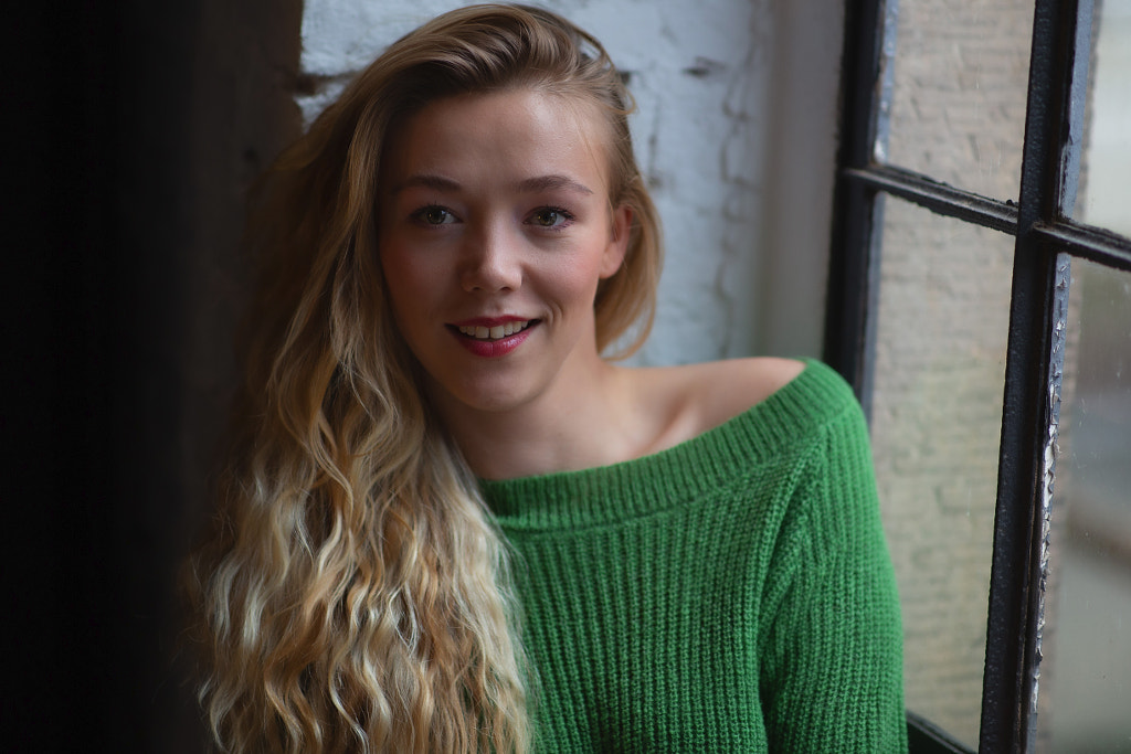 Portrait of smiling young woman sitting at home by Frank Reinbold / 500px