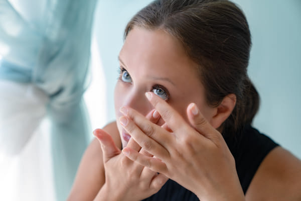 Young grl pulled back her lower eyelid and brought contact lens to her ...