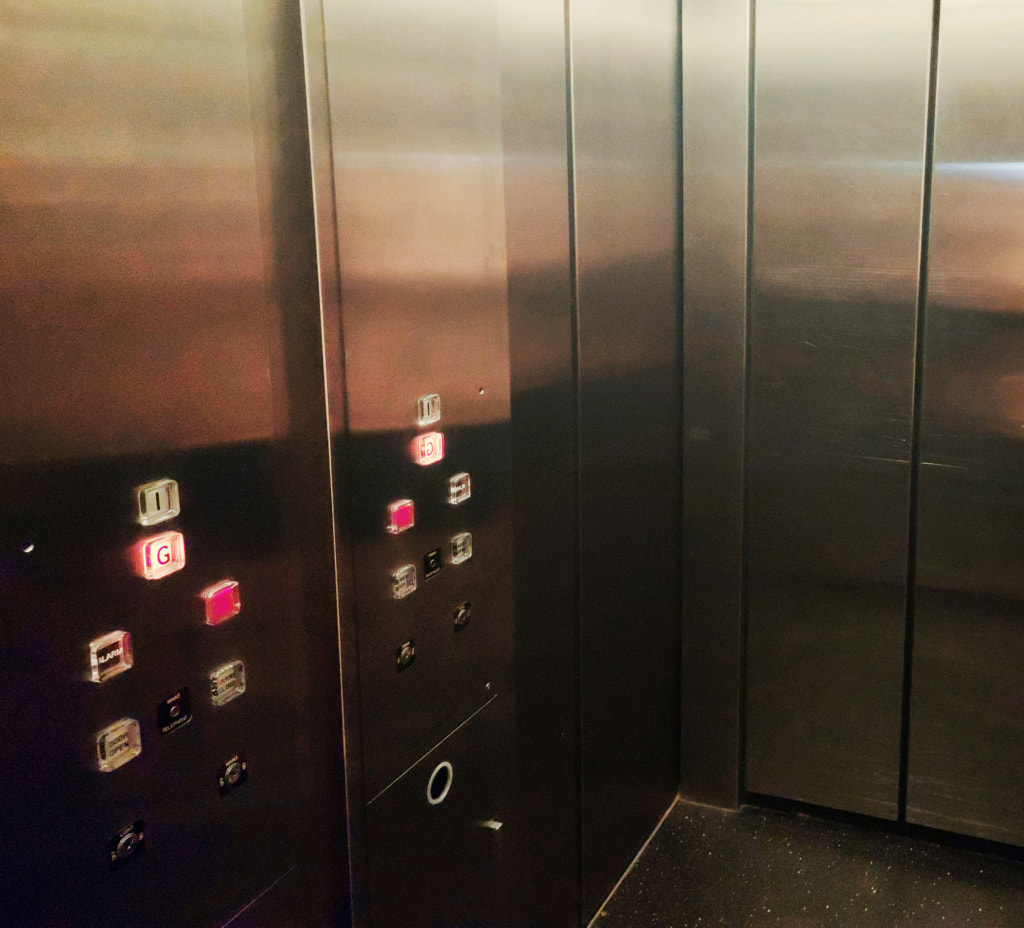 Elevator with button lights and metal doors by Matt Leane / 500px
