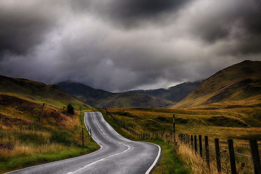 Empty road along landscape against sky by Hilda Murray / 500px