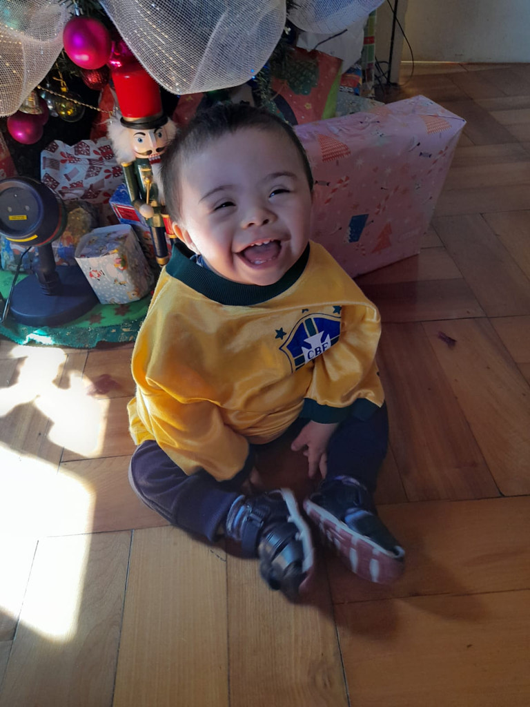 High angle portrait of cute baby boy sitting on hardwood floor at home ...