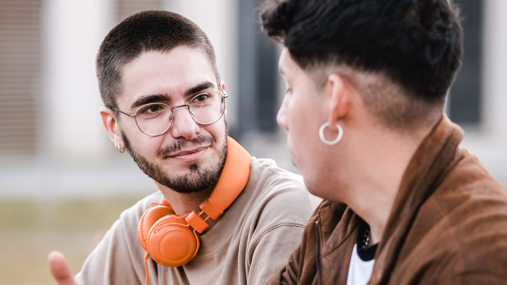 Two cool friends talking and laughing together siting outdoors by ...