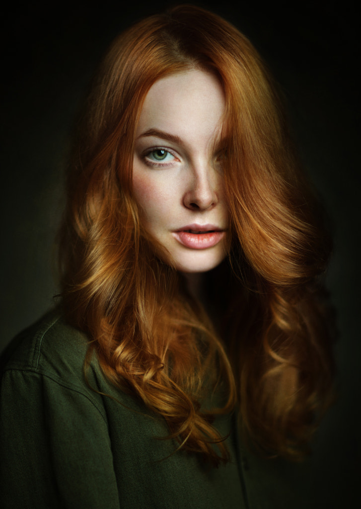 Portrait of beautiful young woman against black background by Zachar ...