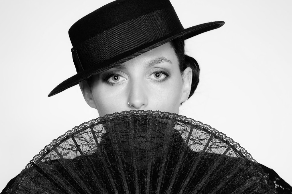 Portrait of young woman with hand fan against white background by Frank ...