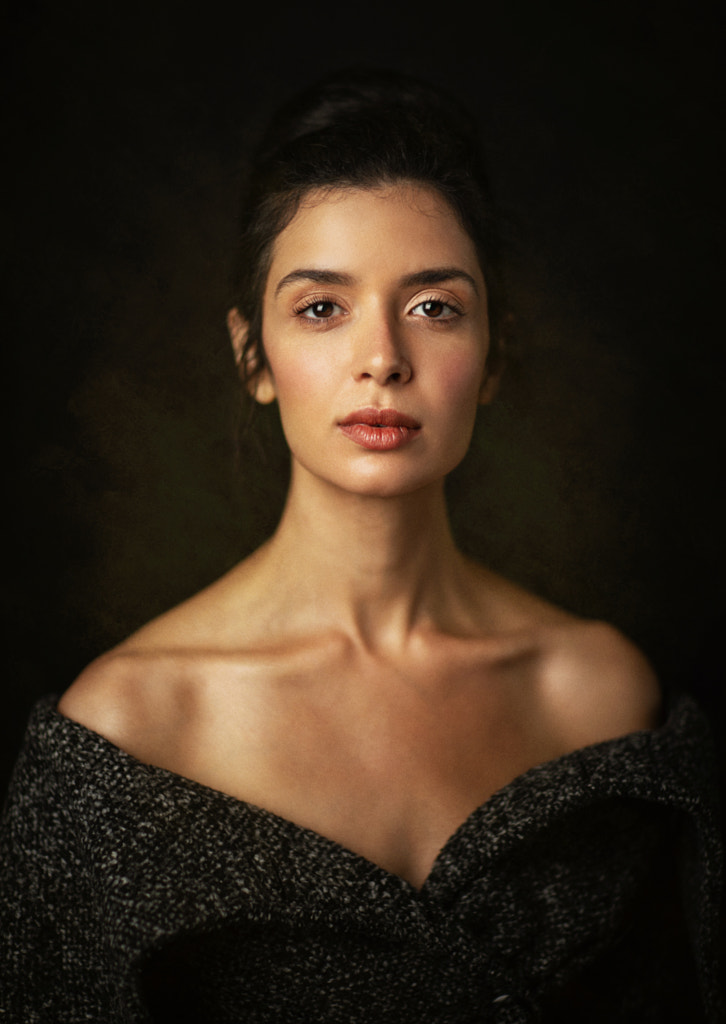 Portrait of beautiful young woman against black background by Zachar ...