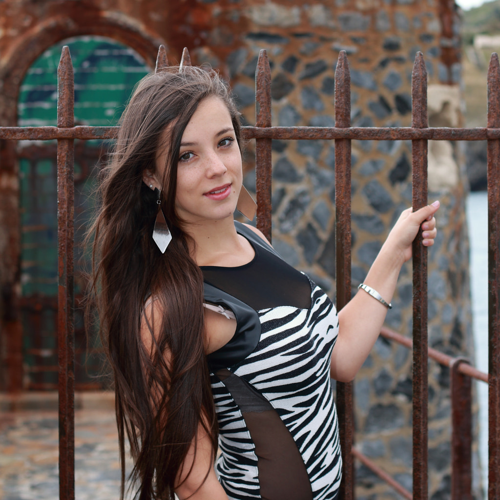 Portrait of beautiful woman standing against gate by Bruno Vilbé / 500px