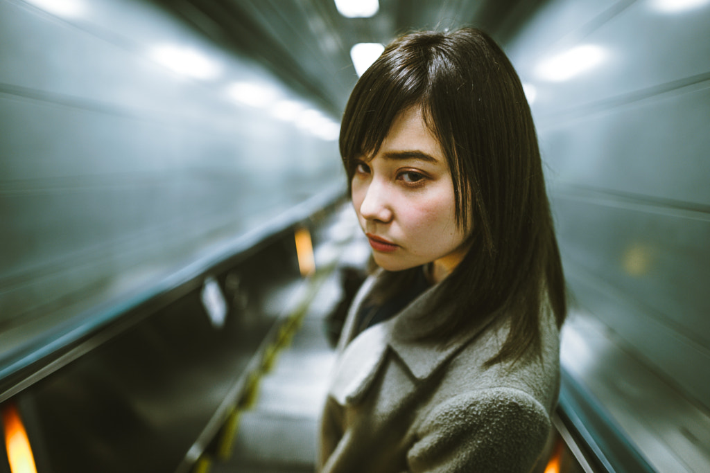 Portrait of young woman standing on escalator by Kaoru Nakamura / 500px