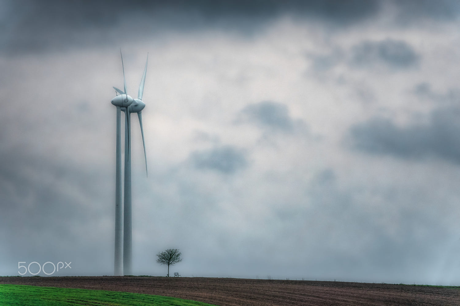 Stormy weather on the horizon - wind turbines and a single tree with a ...