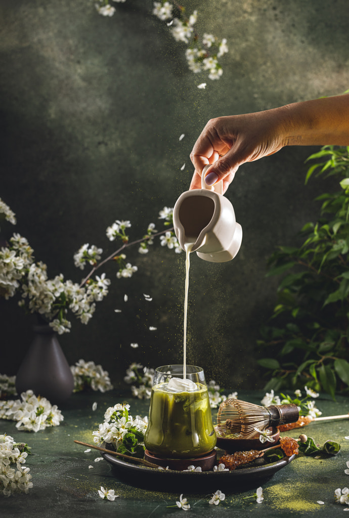 Women hand is pouring homemade sour cream from small jar to glass with ...