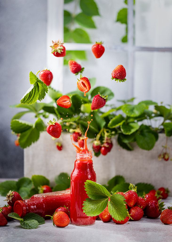 Fresh strawberry juice in a bottle surrounded by many fresh berries ...