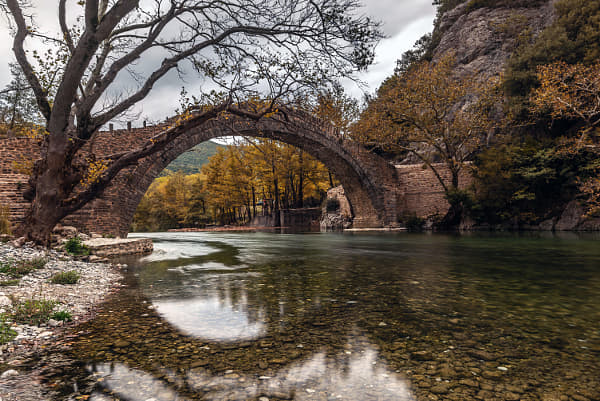 Ancient Stone Bridge Arches Over Reflective River in Autumnal Splendor ...