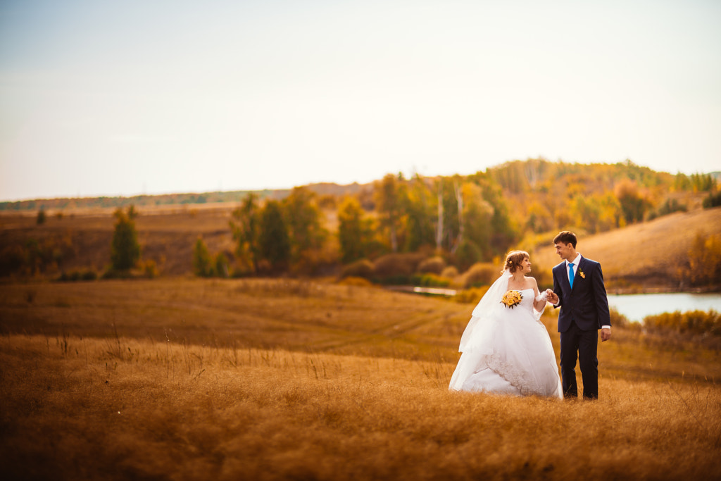 young bride and groom on the background of field by Ruslan Grigoriev ...