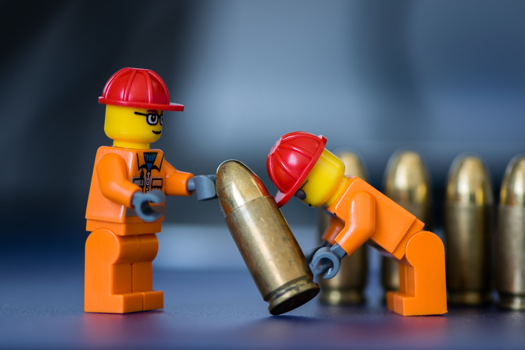 Construction Worker Lego Men Picking Up Bullet by Darren Caiels / 500px