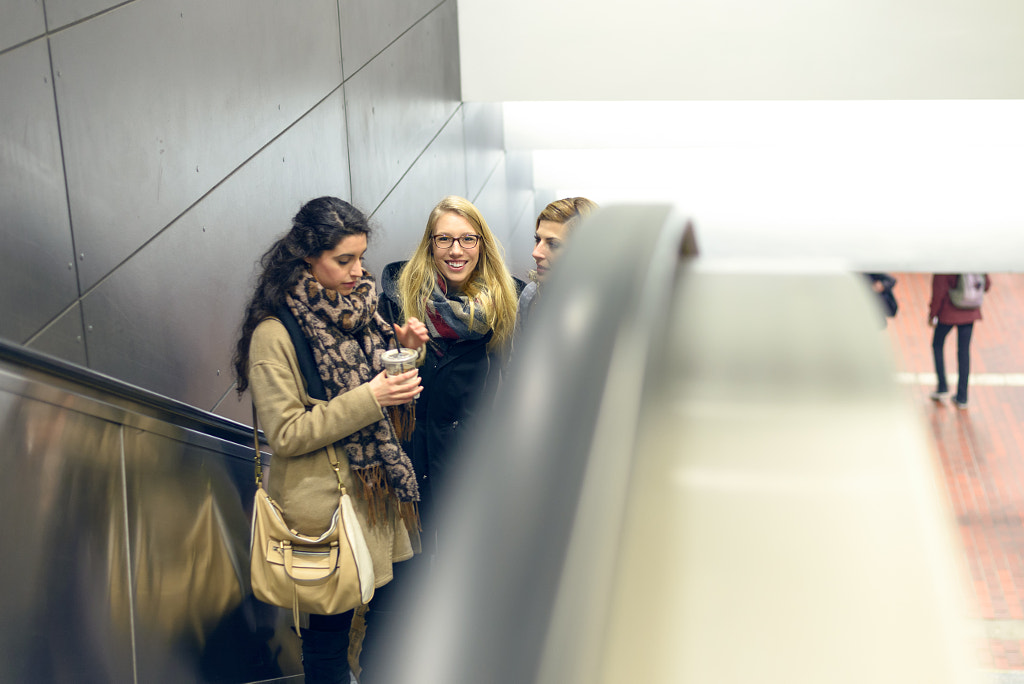 Three women moving up on escalator by Lars Zahner / 500px