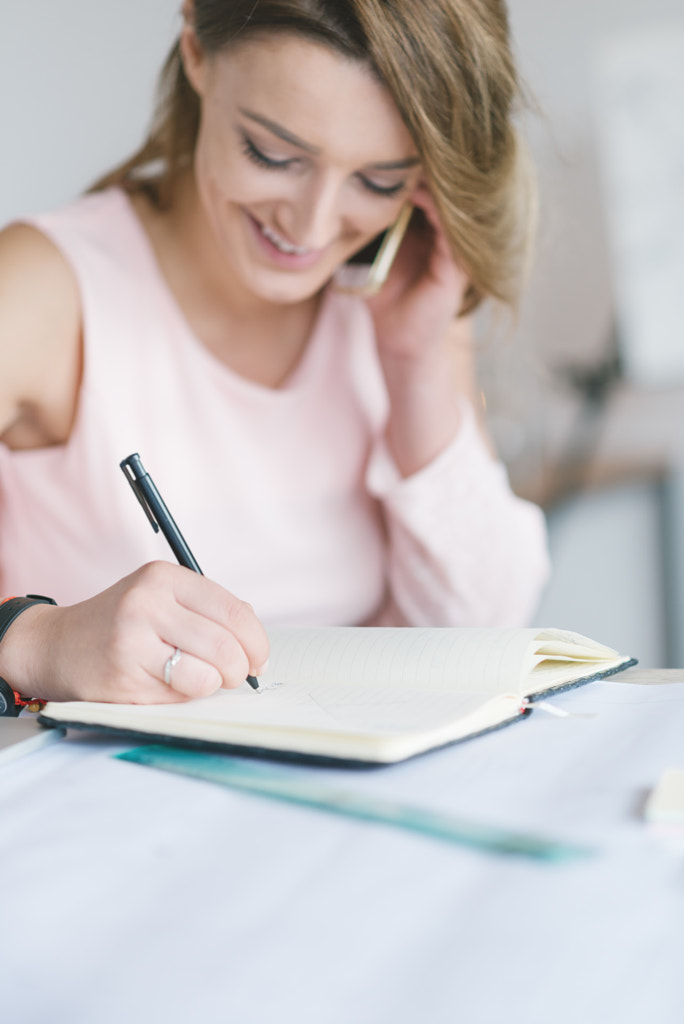 Young smiling businesswoman working in her office by Igor Milic / 500px