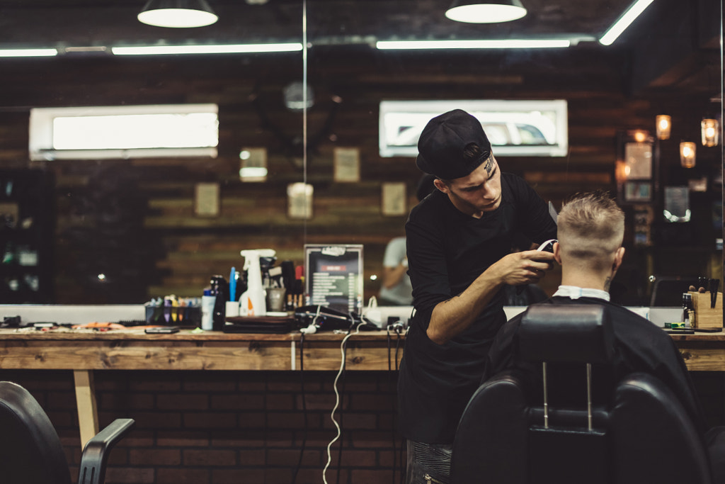 Crop barber doing haircut for client by Konstantin Kolosov / 500px