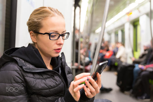 Young girl reading from mobile phone screen in metro. by Matej Kastelic ...